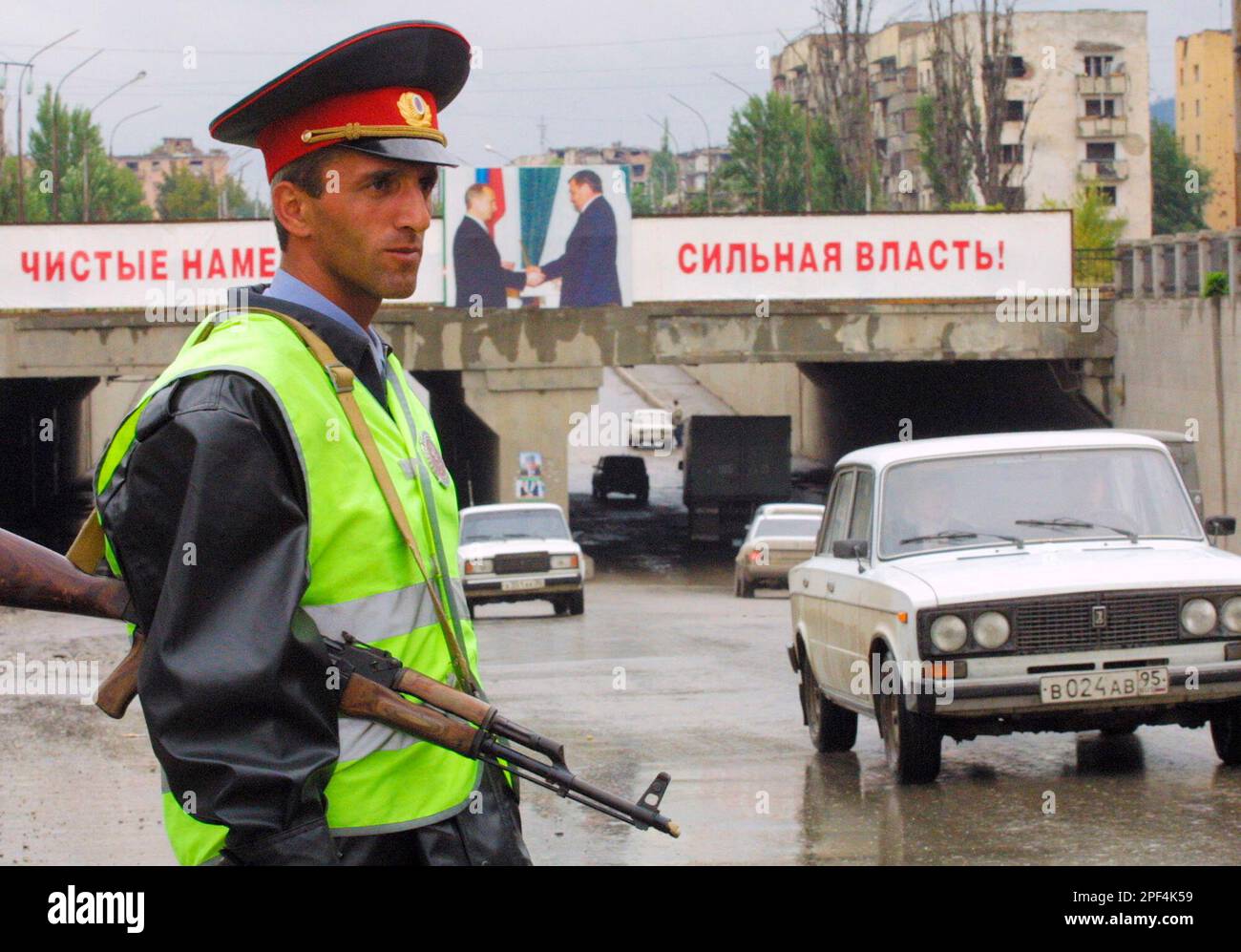 A Chechen police officer stands at a pre-election poster, which depicts ...