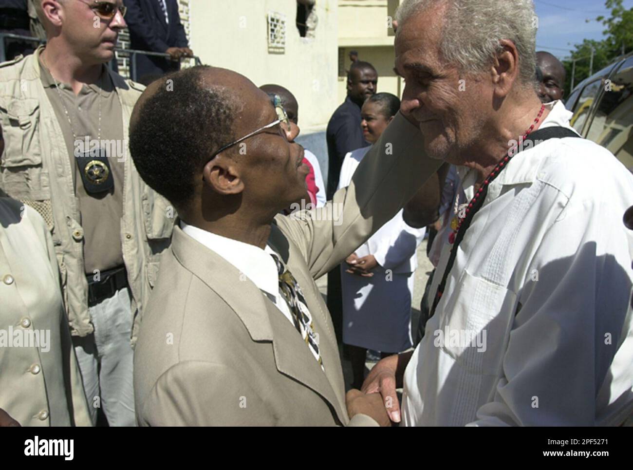 Haitian President Jean-Bertrand Aristide, left, pats the head of Father ...