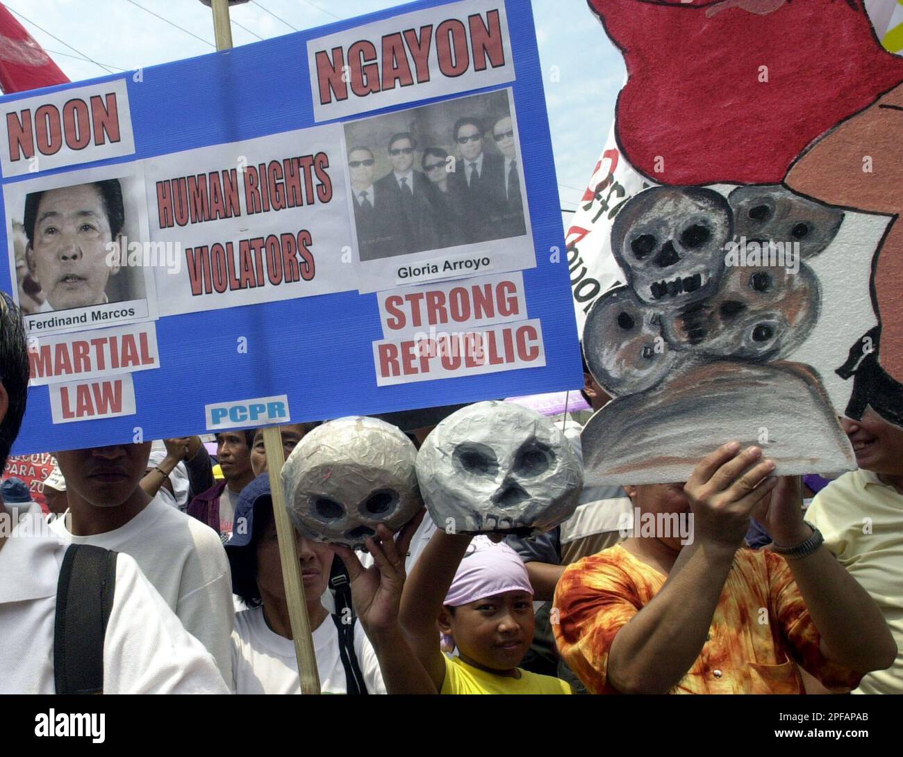 Leftist protesters display a placard and mock skulls as they march ...