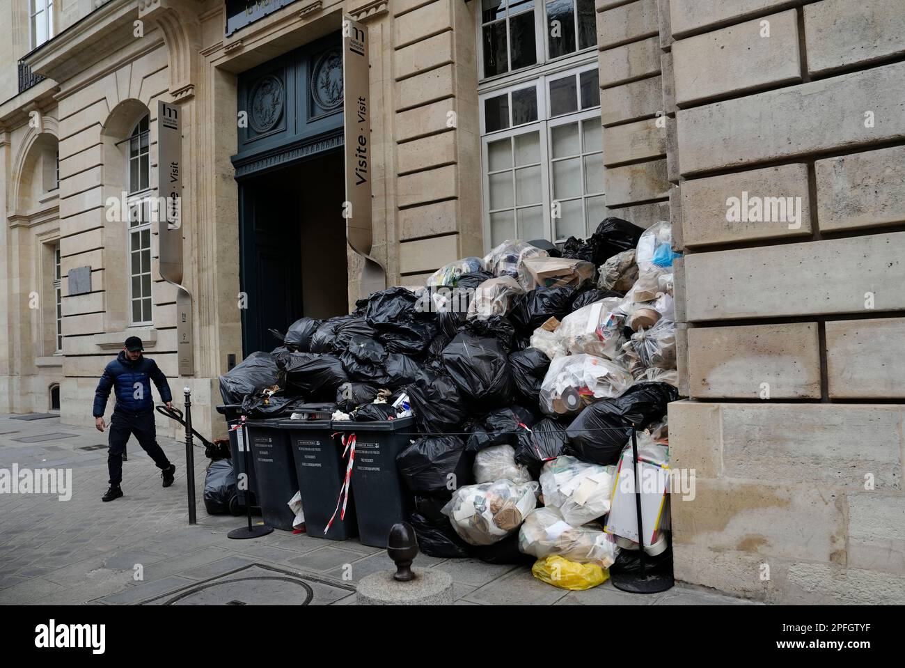A man walks past uncollected garbages in Paris, Friday March 17, 2023 ...