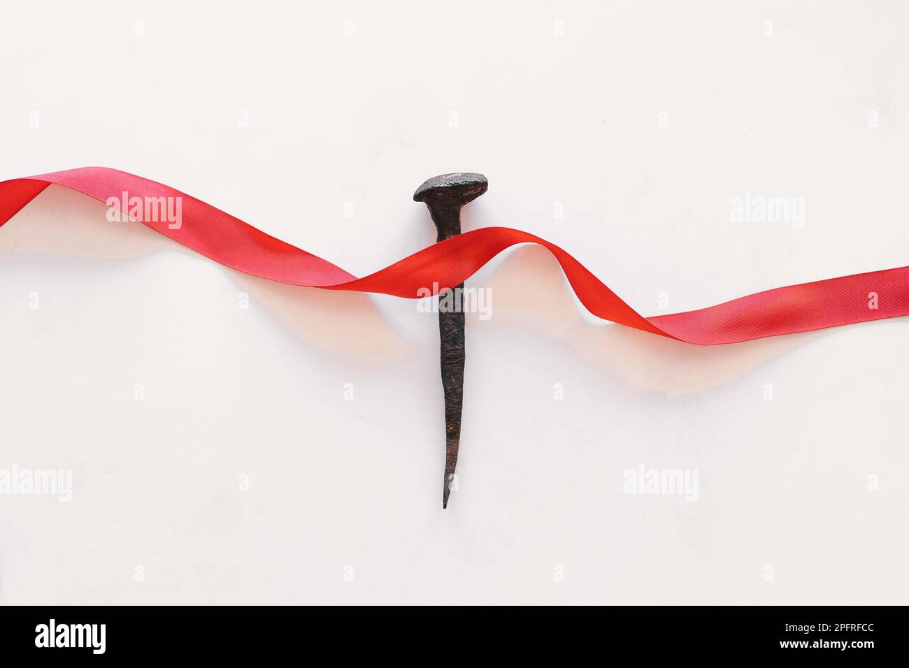 Un clou avec un ruban rouge, un symbole du Christ. Crucifixion de Jésus ...