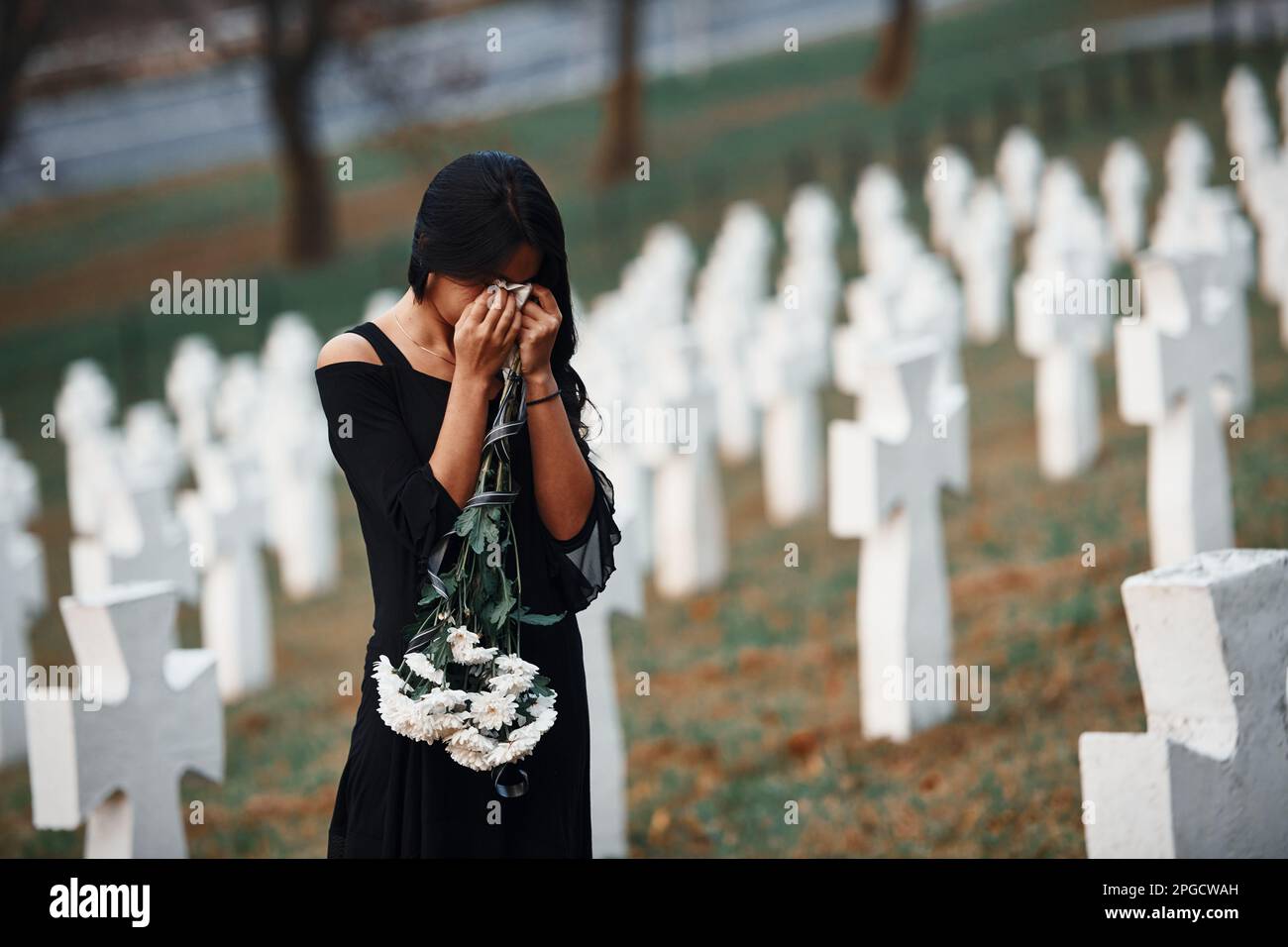 Avec des fleurs entre les mains. Jeune femme en vêtements noirs ...
