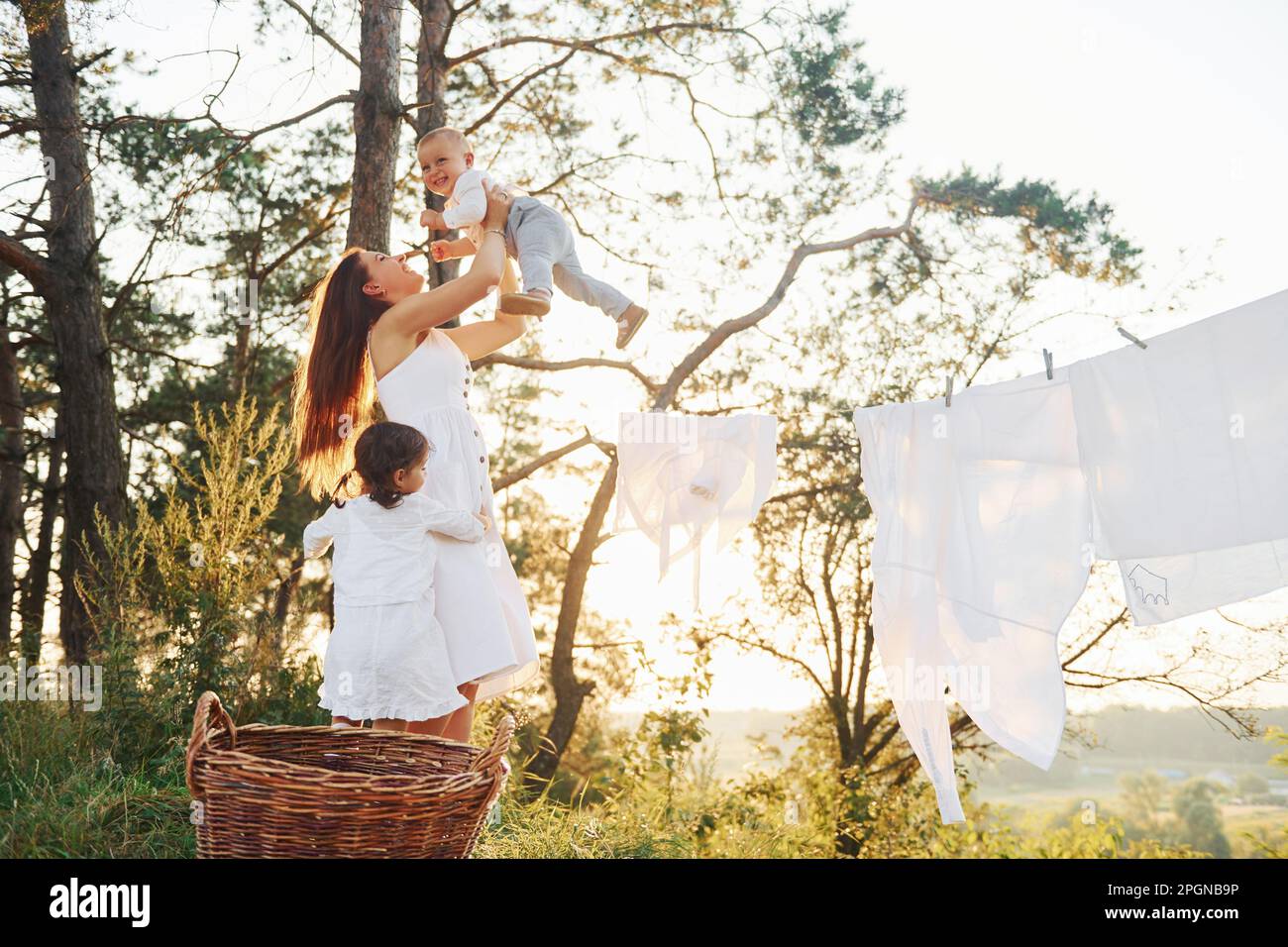 Vêtements blancs suspendus sur la corde pour sécher. Une jeune mère ...