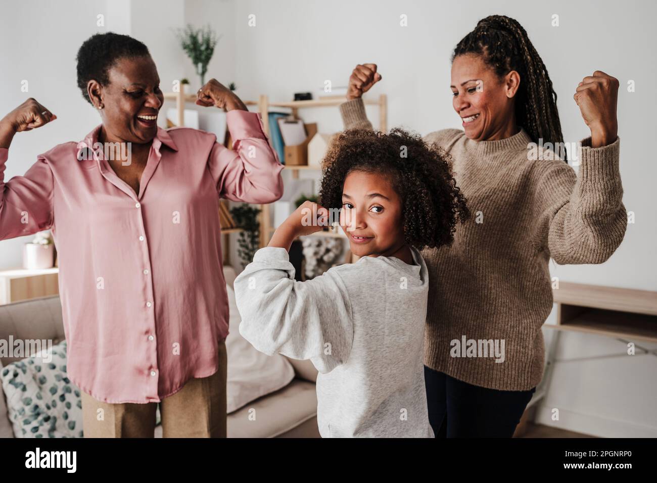 Fille flexion de muscles avec la mère et la grand-mère à la maison ...