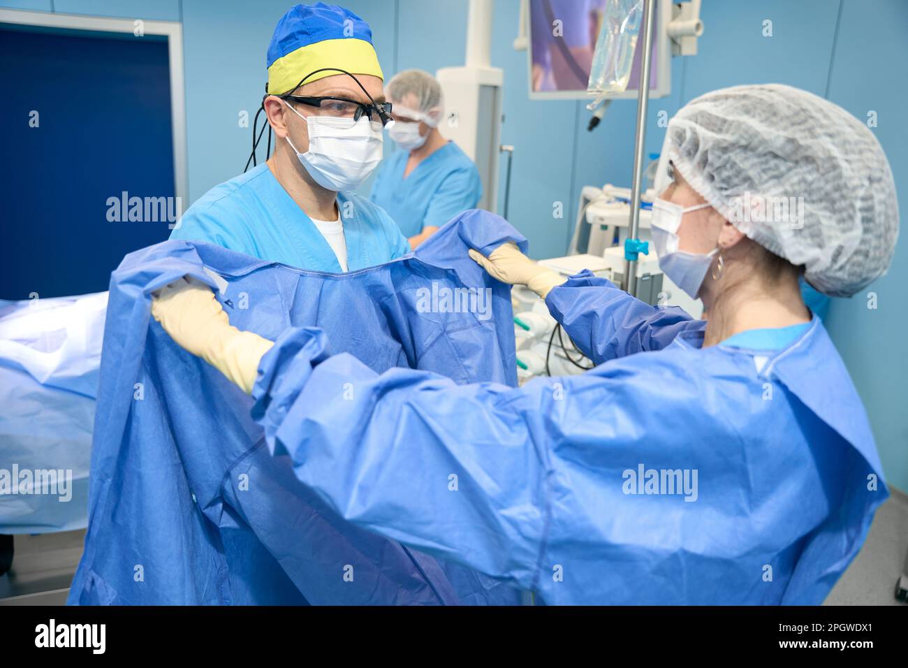 L'infirmière aide le médecin à mettre une robe stérile Photo Stock - Alamy