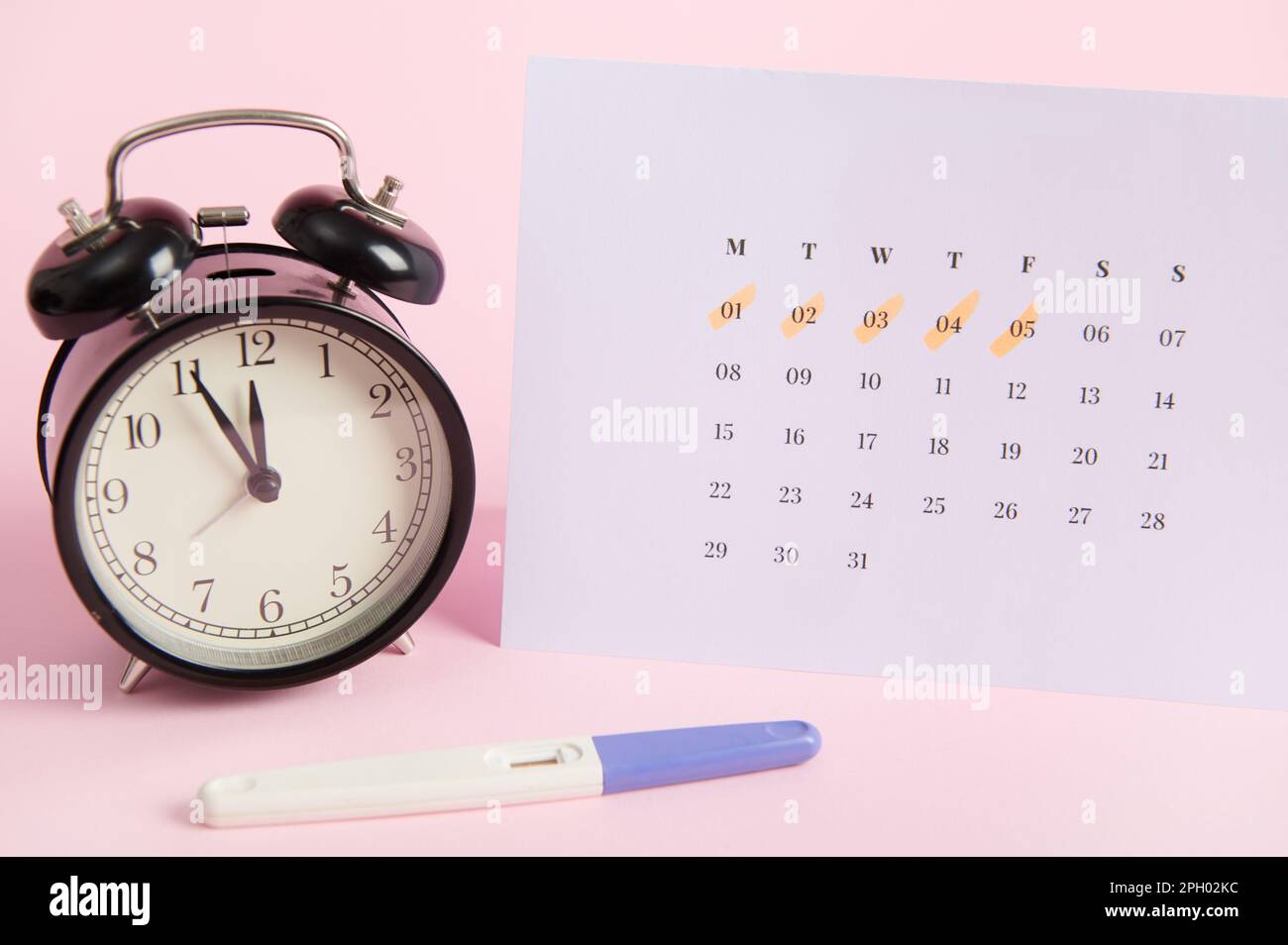 Test de grossesse positif, réveil et calendrier blanc avec les dates de ...