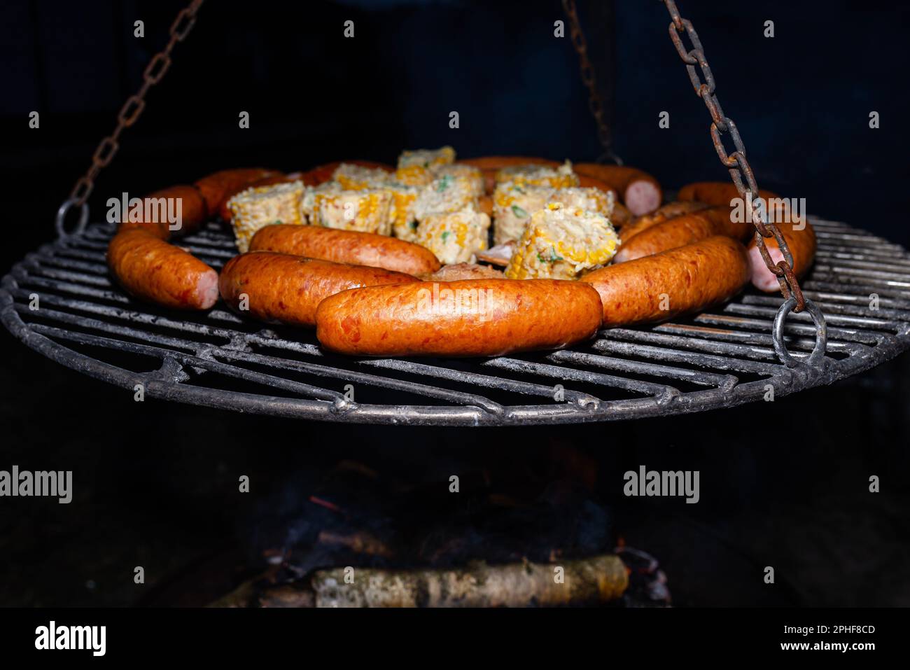 Cuisson de saucisses, de fromage de mouton et de maïs sur une grille ...