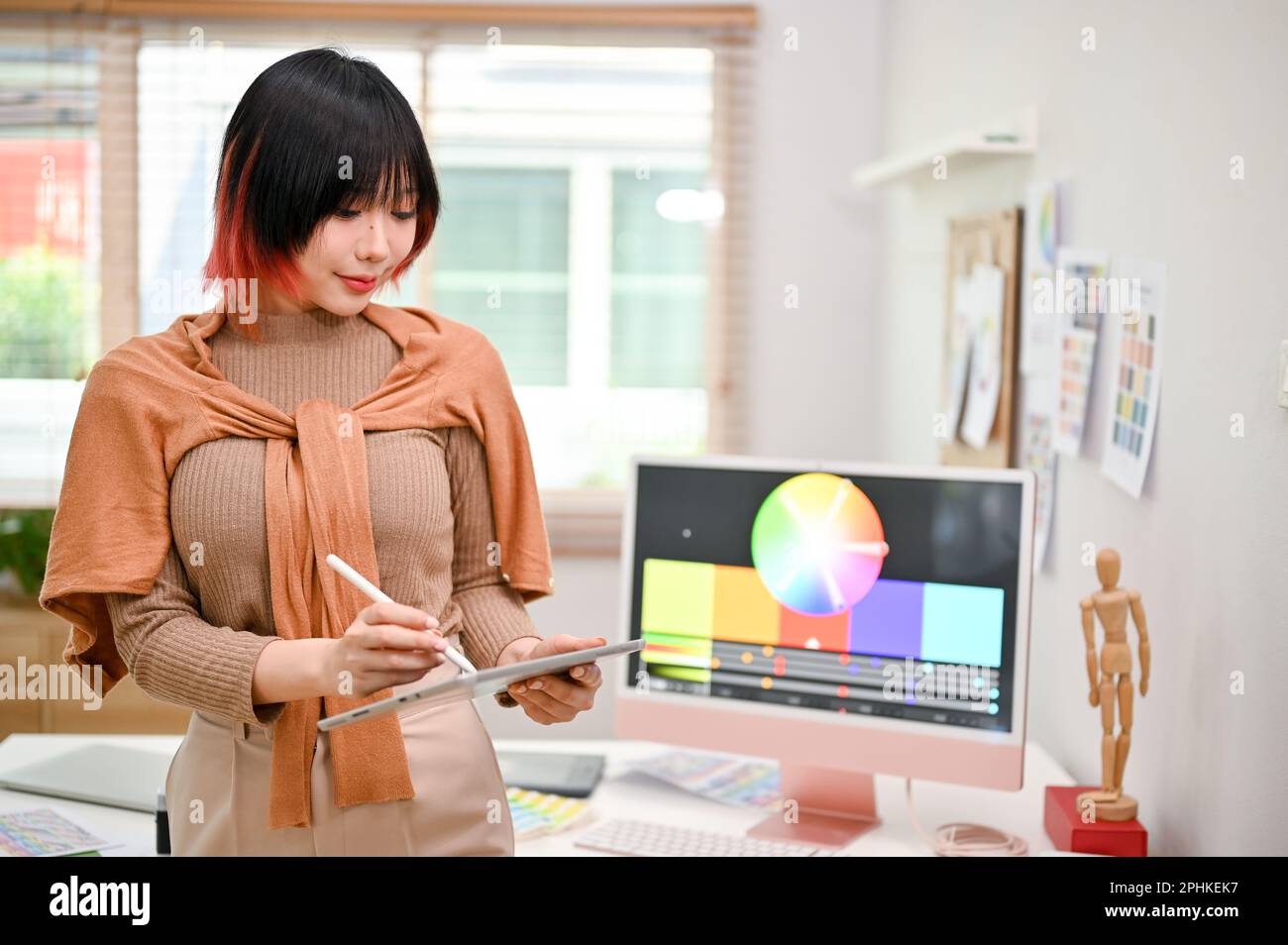 Une jeune femme de graphiste asiatique se tient dans son studio et ...
