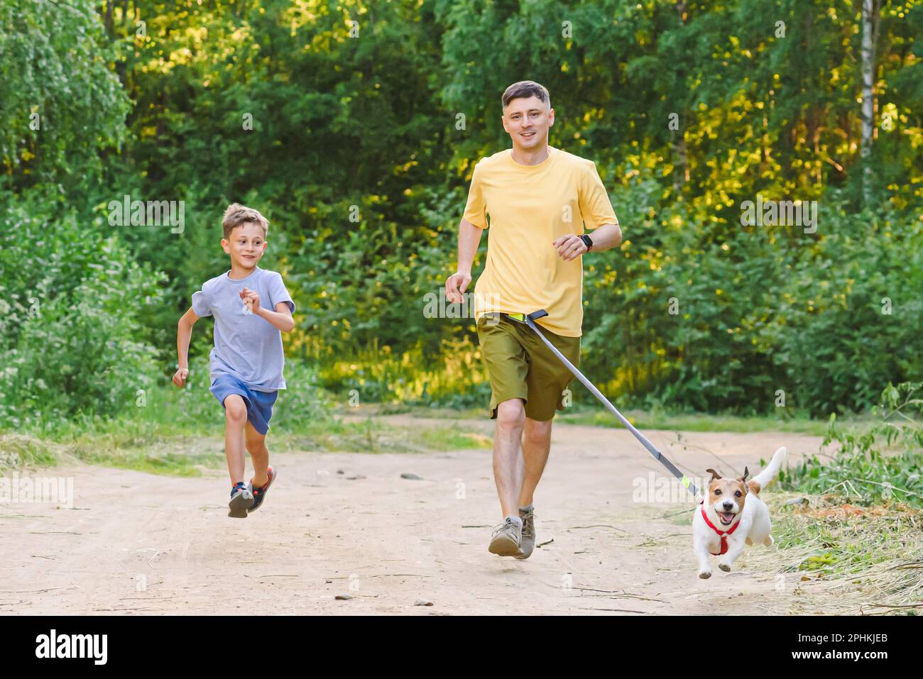 Le père et le fils font du jogging le long de la route de terre de ...