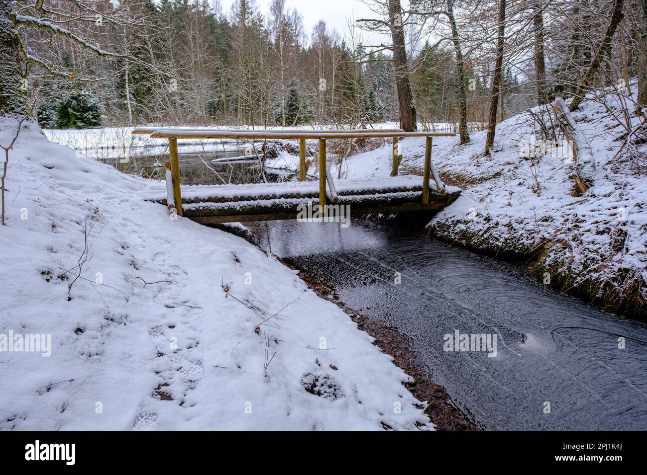 Pont en bois recouvert de neige au-dessus d'une petite rivière Photo ...