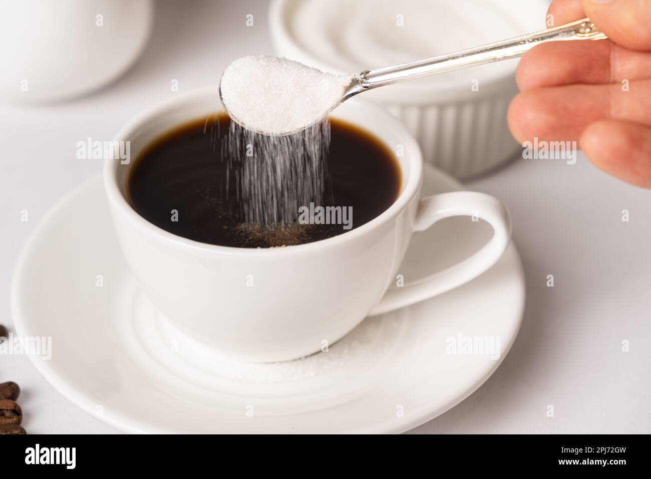 Le processus de verser le sucre blanc d'une cuillère dans une tasse de ...