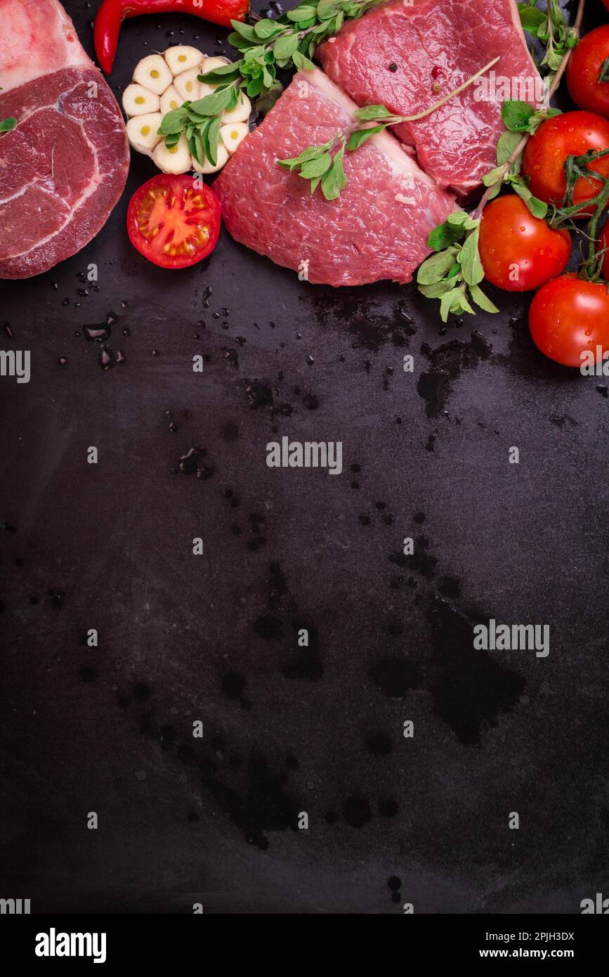 Viande juteuse crue prête à rôtir sur fond noir de tableau à craie ...