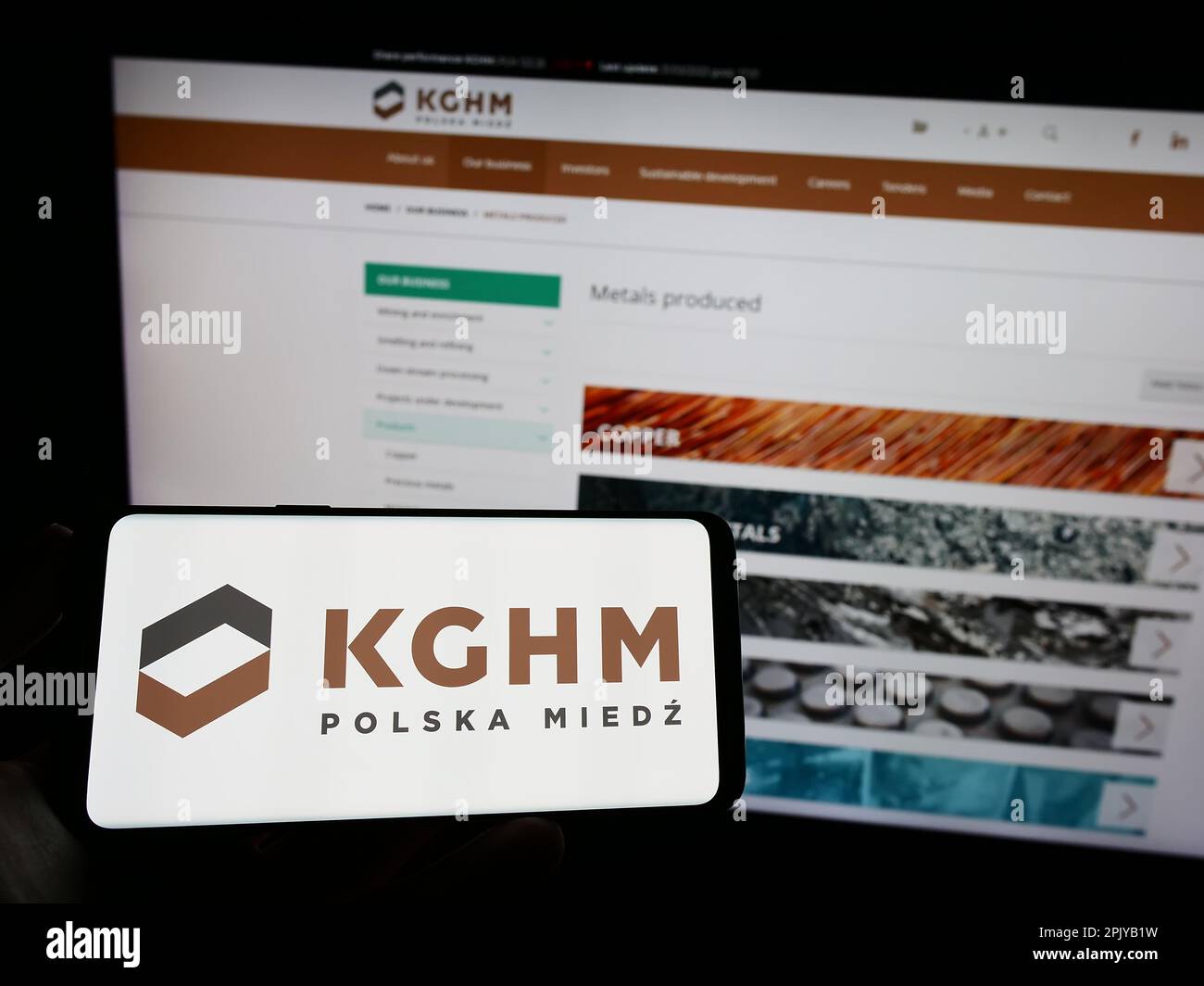 Personne tenant un téléphone portable avec le logo de la société minière polonaise KGHM Polska ...