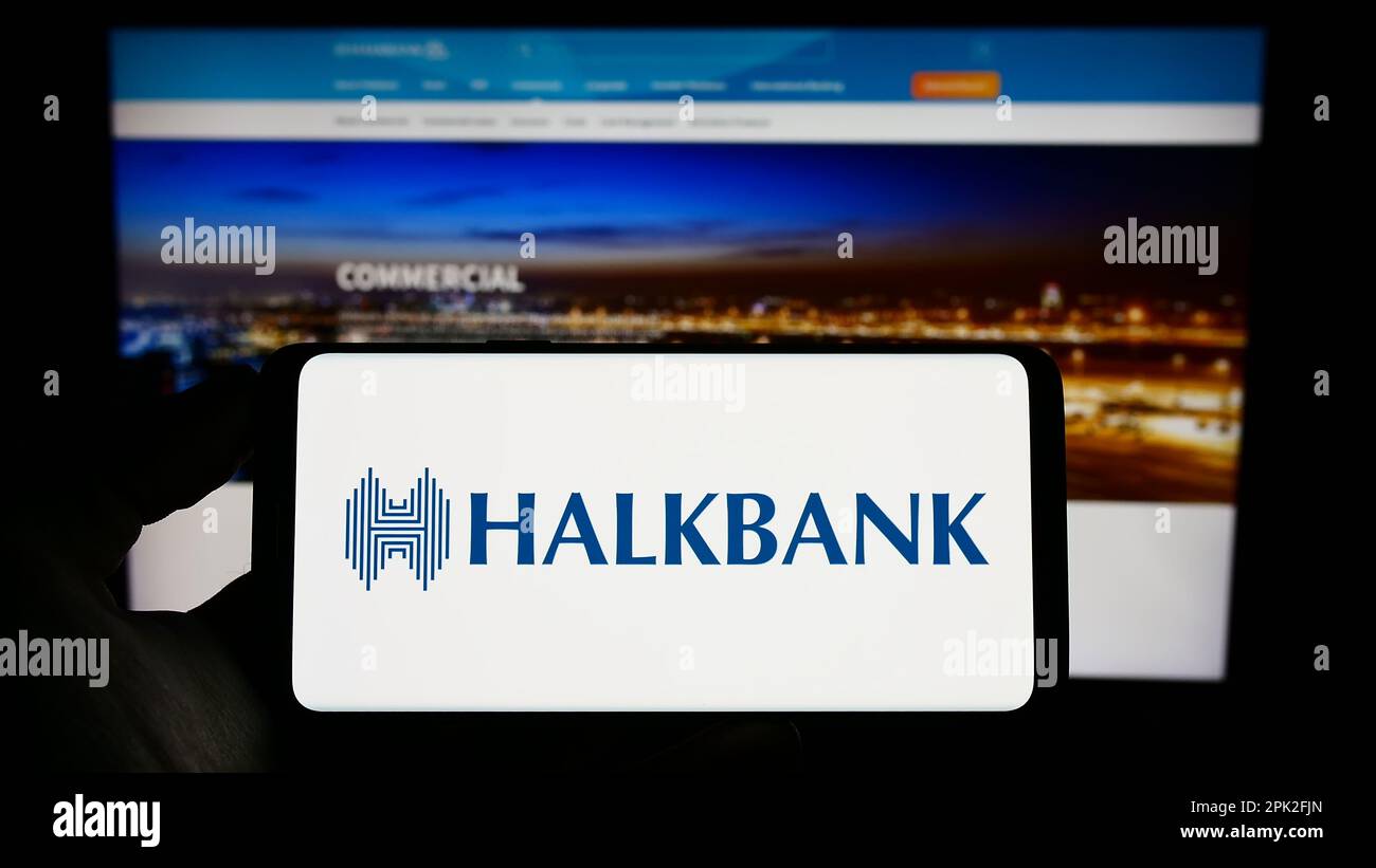 Personne tenant un téléphone portable avec le logo de la société Turkiye Halk Bankasi A.S ...