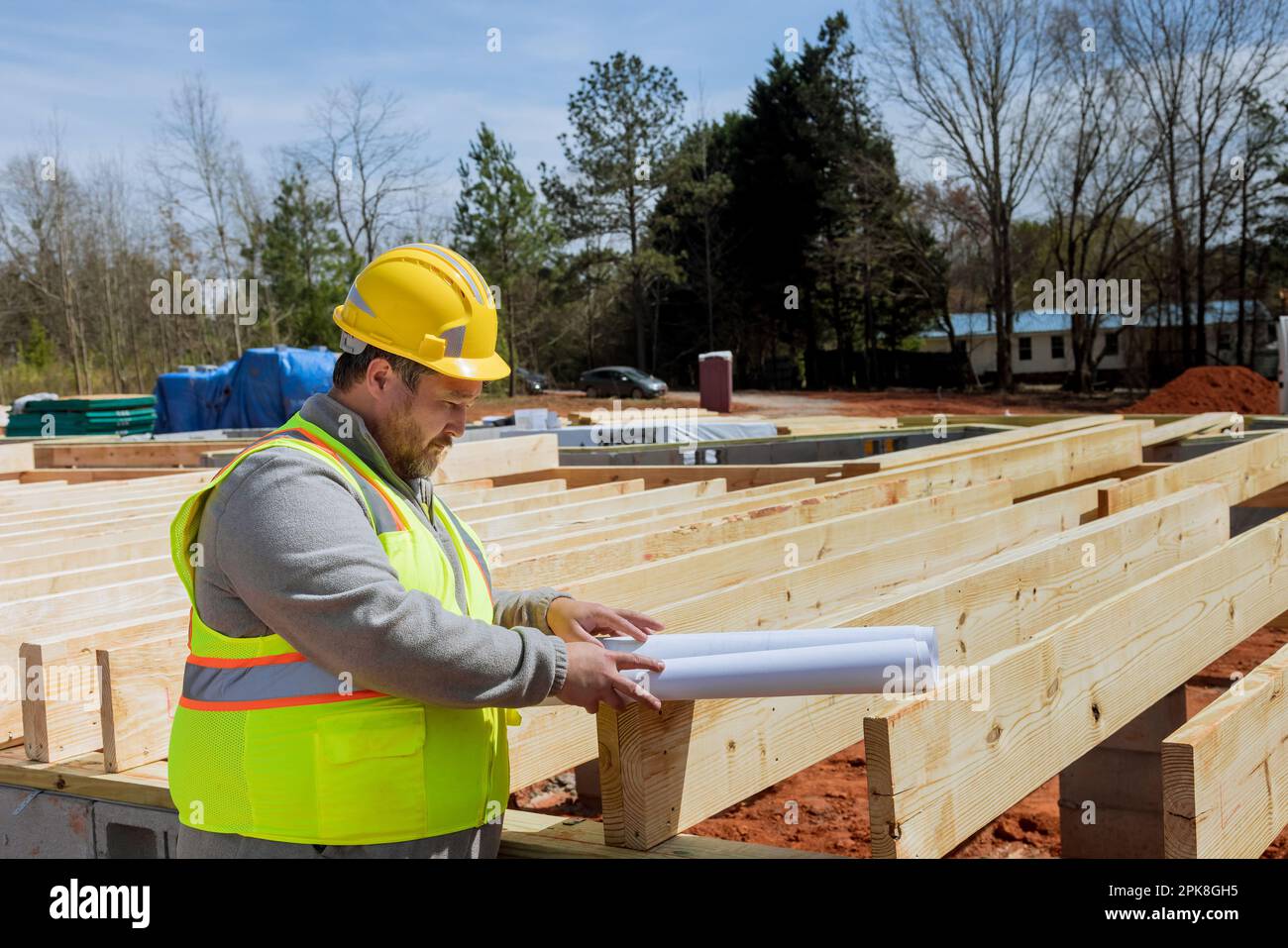 Sur le chantier de construction, le superviseur portant un casque de sécurité vérifie le plan du ...