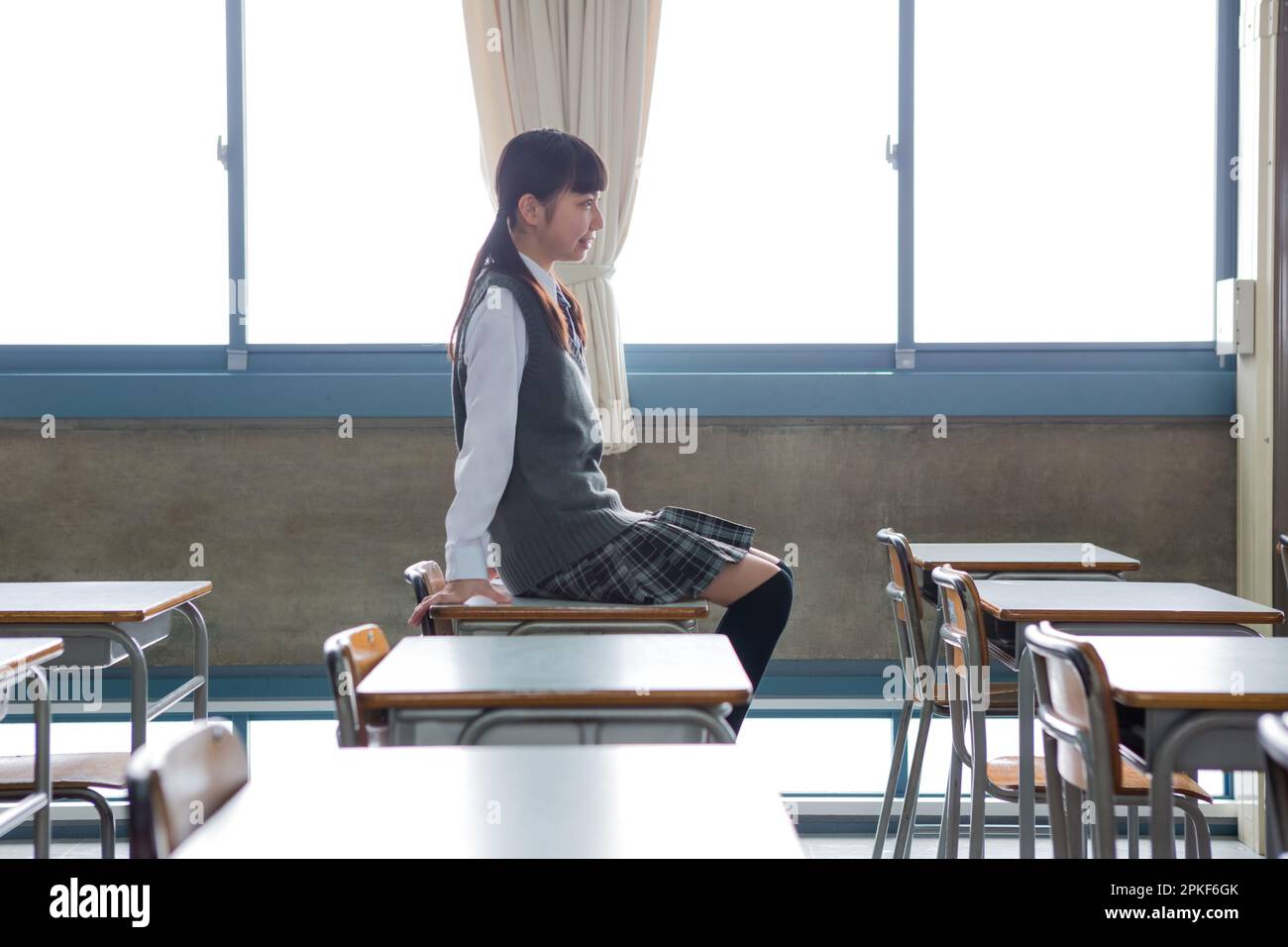 Une jeune fille d'école secondaire assise à un bureau dans une salle de ... Une jeune fille d'école secondaire assise à un bureau dans une salle de ...