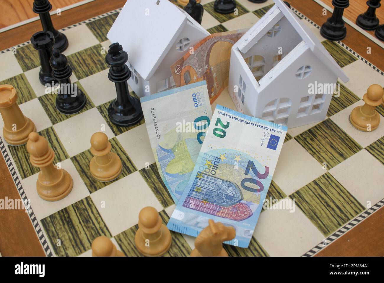 pièces d'échecs, billets d'euros et maisons sur le plateau d'échecs ...