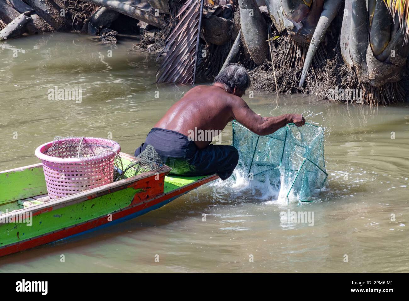 Un pêcheur sur un bateau vérifie les pièges à filet qu'il tire de l'eau ...