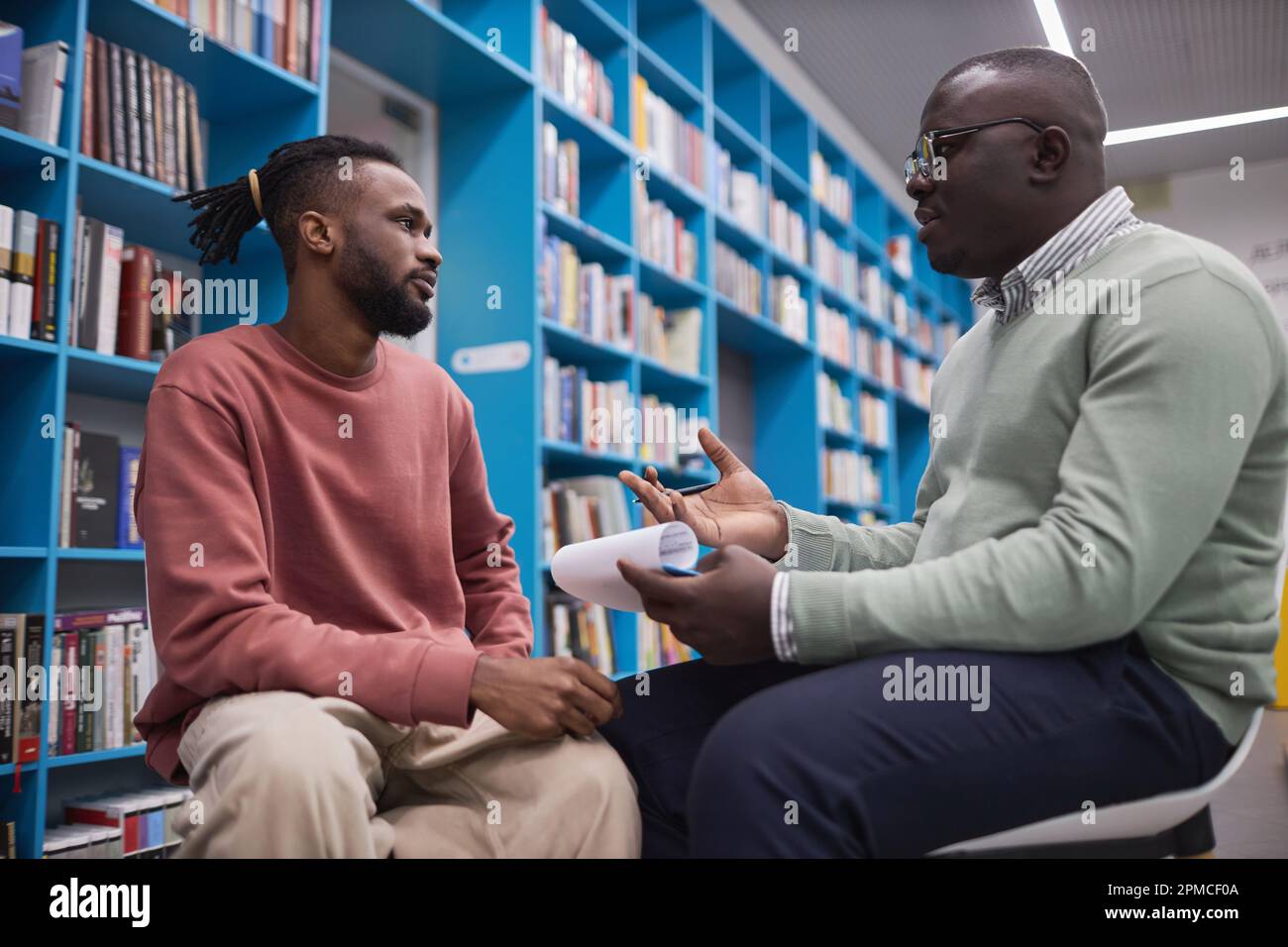 Portrait de côté d'un thérapeute afro-américain parlant à un étudiant ...