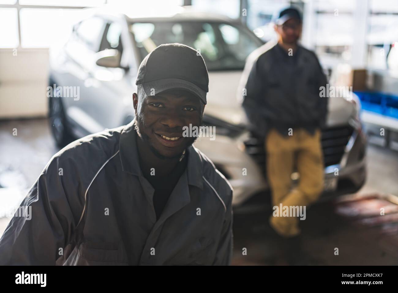 Portrait d'un mécanicien automobile africain positif en uniforme posant après le travail, il est ...