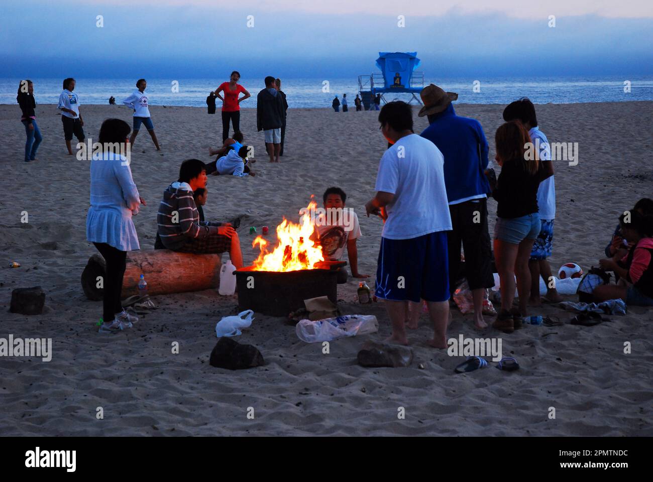 Les amis et la famille se rassemblent autour d'un feu de joie sur la plage de Santa Cruz en ...