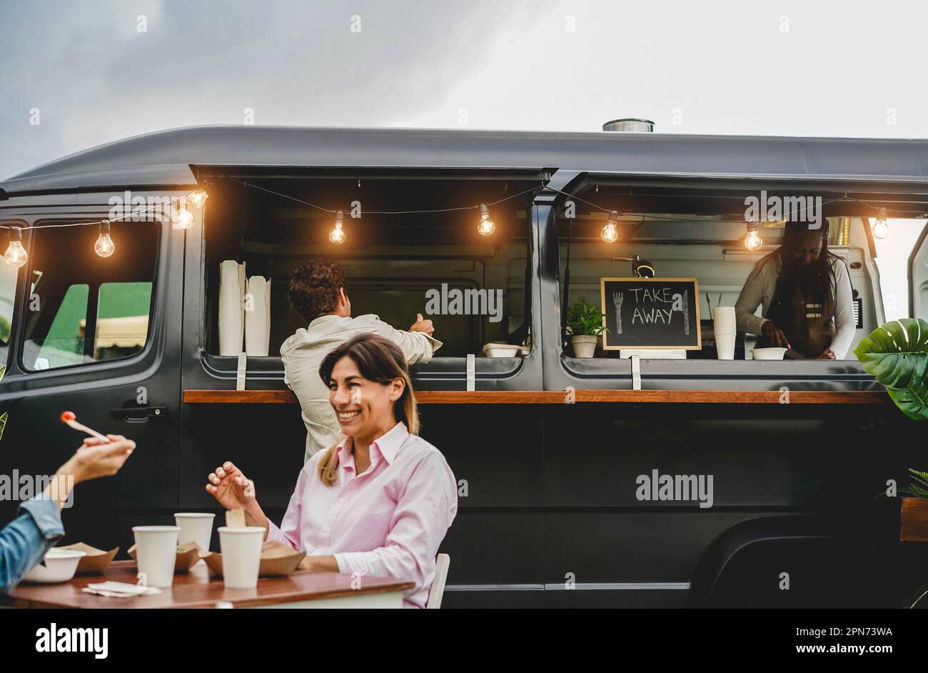 Des gens heureux qui s'amusent à manger et à boire à l'extérieur au ...
