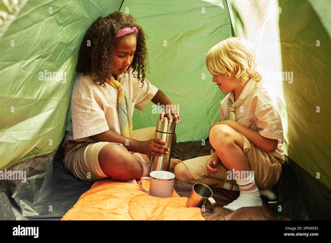 Portrait en longueur de deux jeunes scouts assis dans une tente et ...