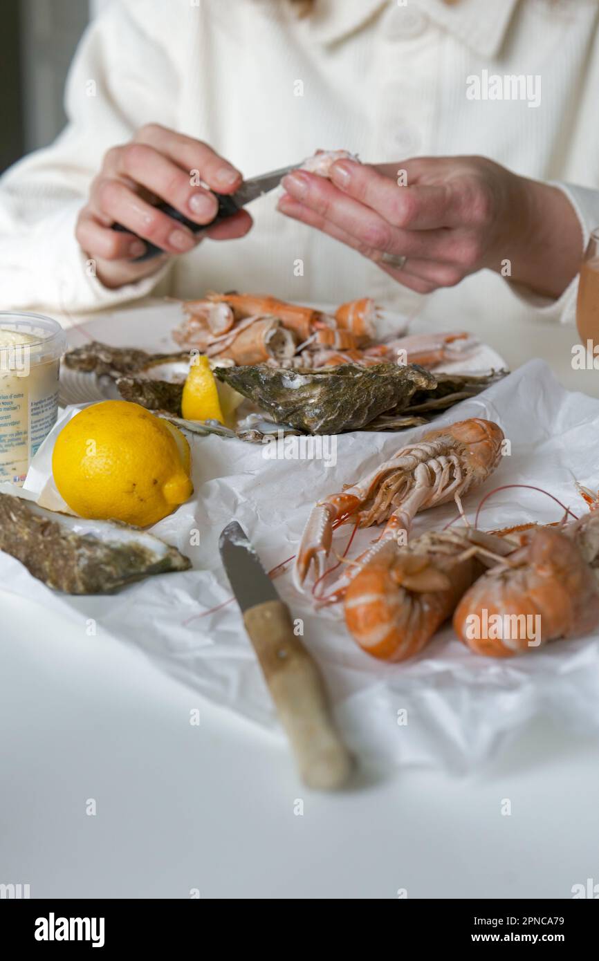 Femme ouvrant des crevettes au-dessus de la table pleine de fruits de ...