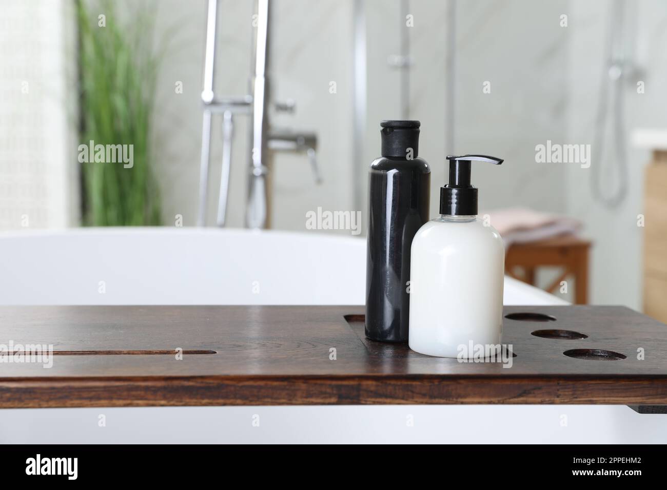Plateau de bain en bois avec bouteilles de gels douche sur la baignoire ...