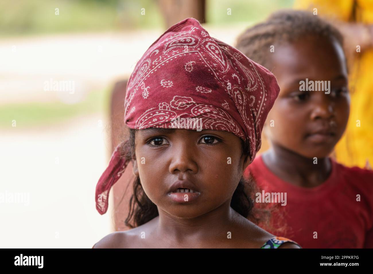 Petite fille malgache mignonne avec un foulard sur la tête jouant femme ...