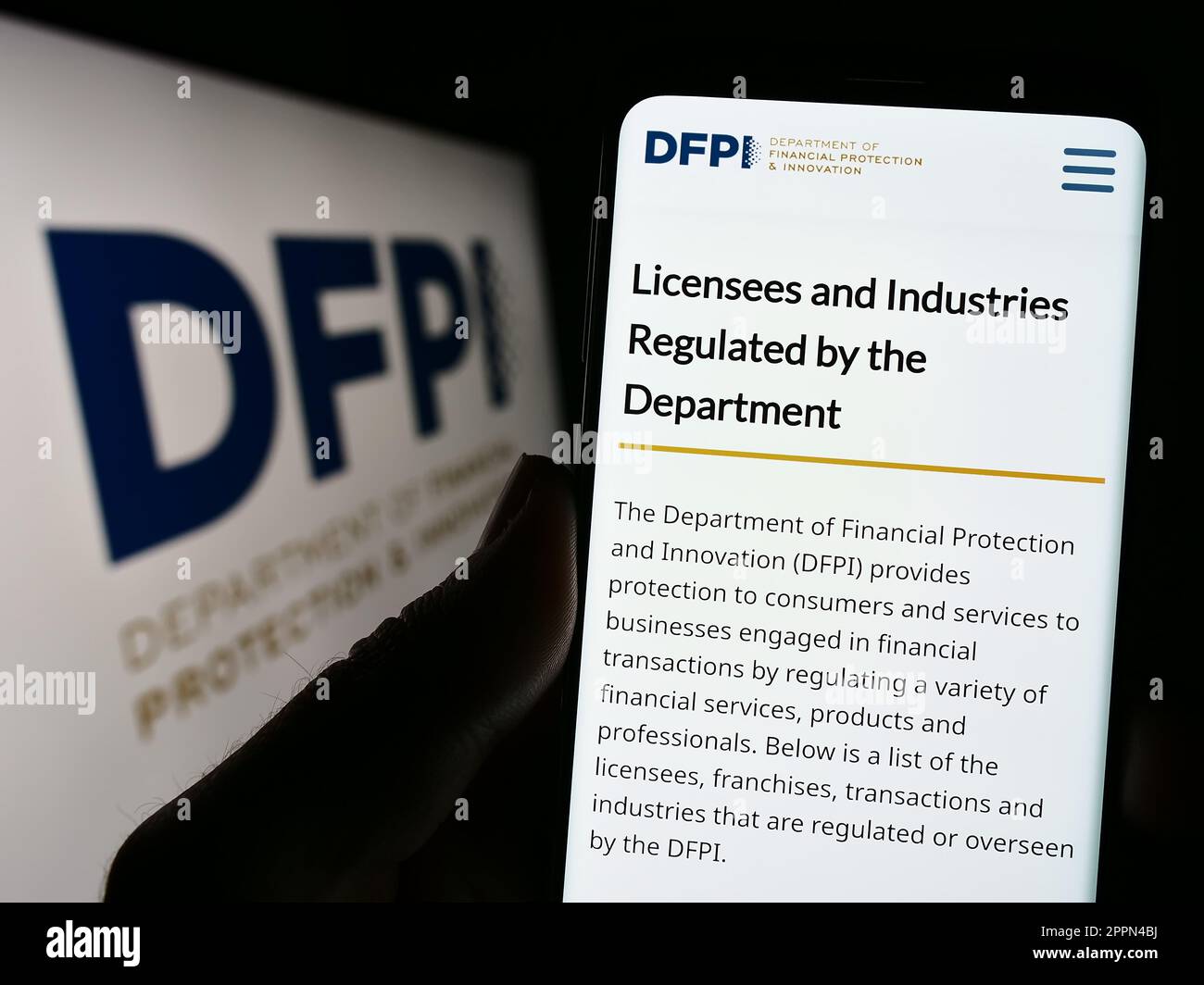 Personne tenant le téléphone portable avec la page web du département californien DFPI à l'écran ...