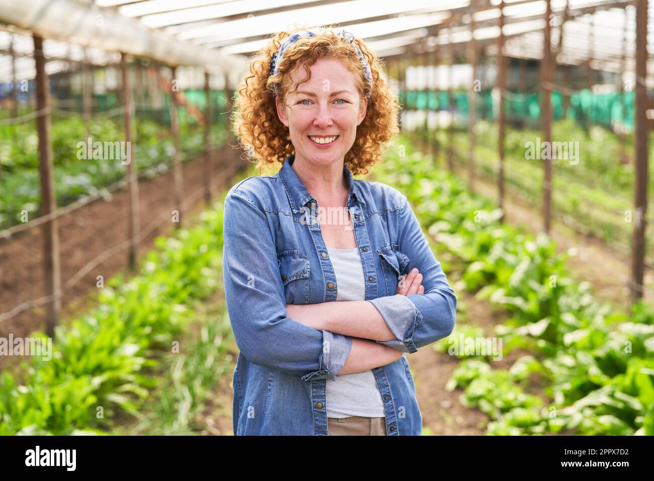Portrait d'une fermière mûre heureuse debout avec les bras croisés dans ...
