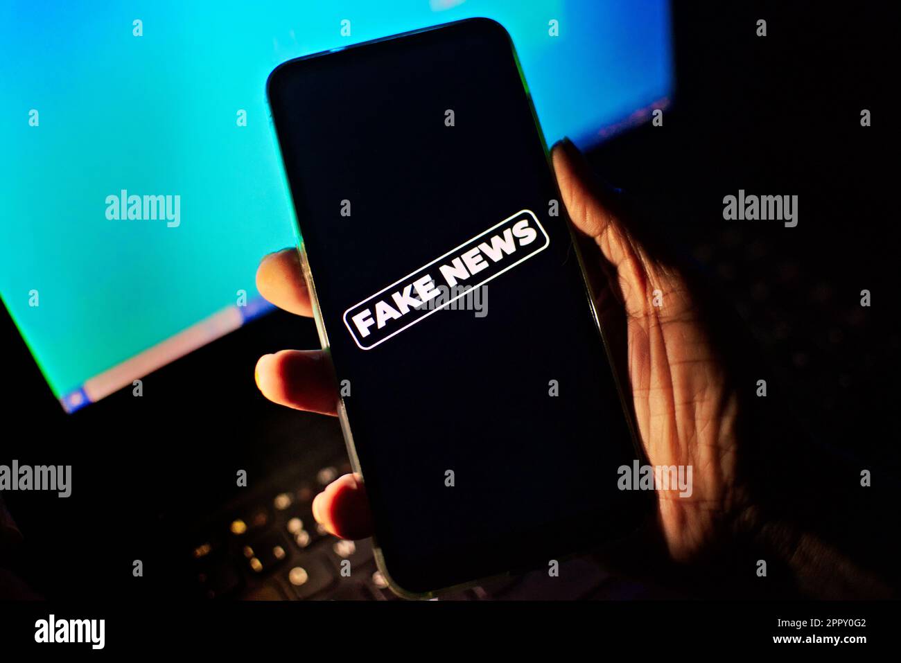 Main tenant un téléphone cellulaire où les mots fake news sont affichés ...