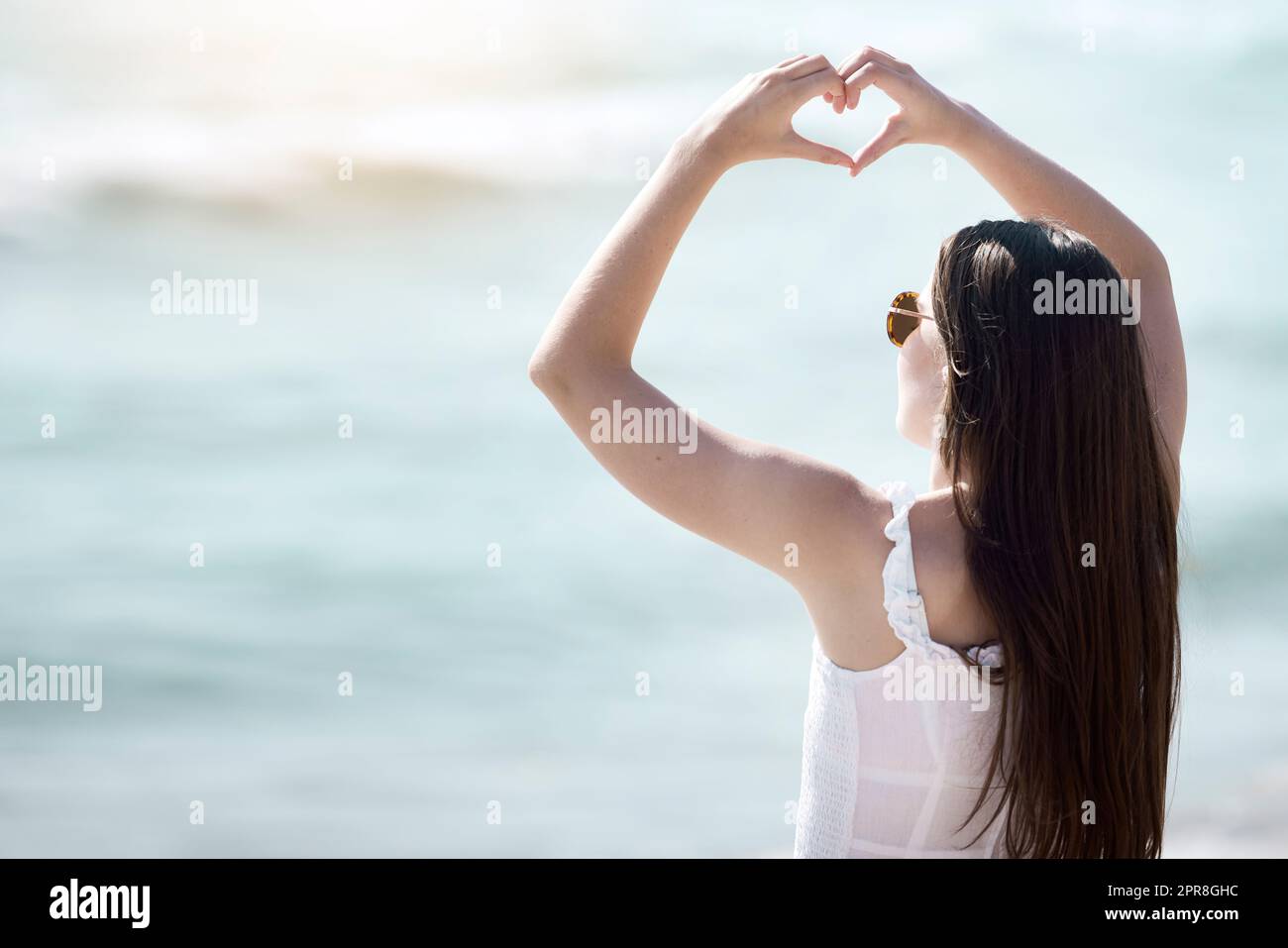 Mon coeur est avec l'océan. Une jeune femme faisant un geste de coeur ...