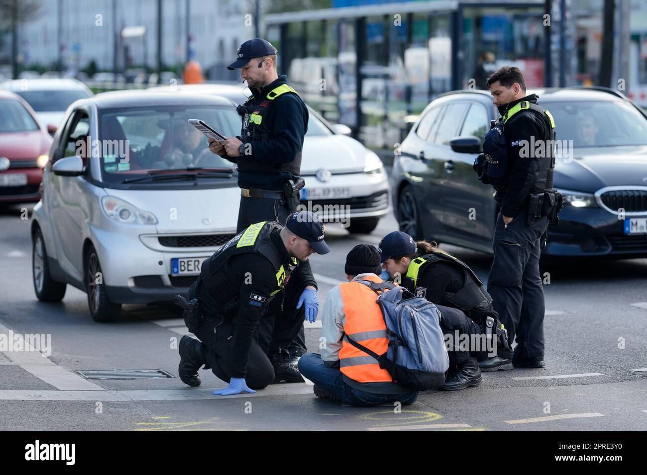Police officers remove the glued hand of a climate activist from a road ...
