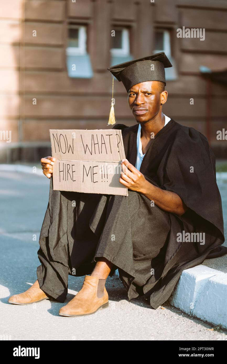 Un gars noir contrarié assis avec une affiche en carton dans la rue à ...