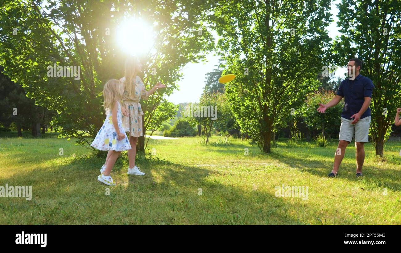 Une famille caucasienne lance un disque de Frisbee dans le parc à l'extérieur. Des filles ...