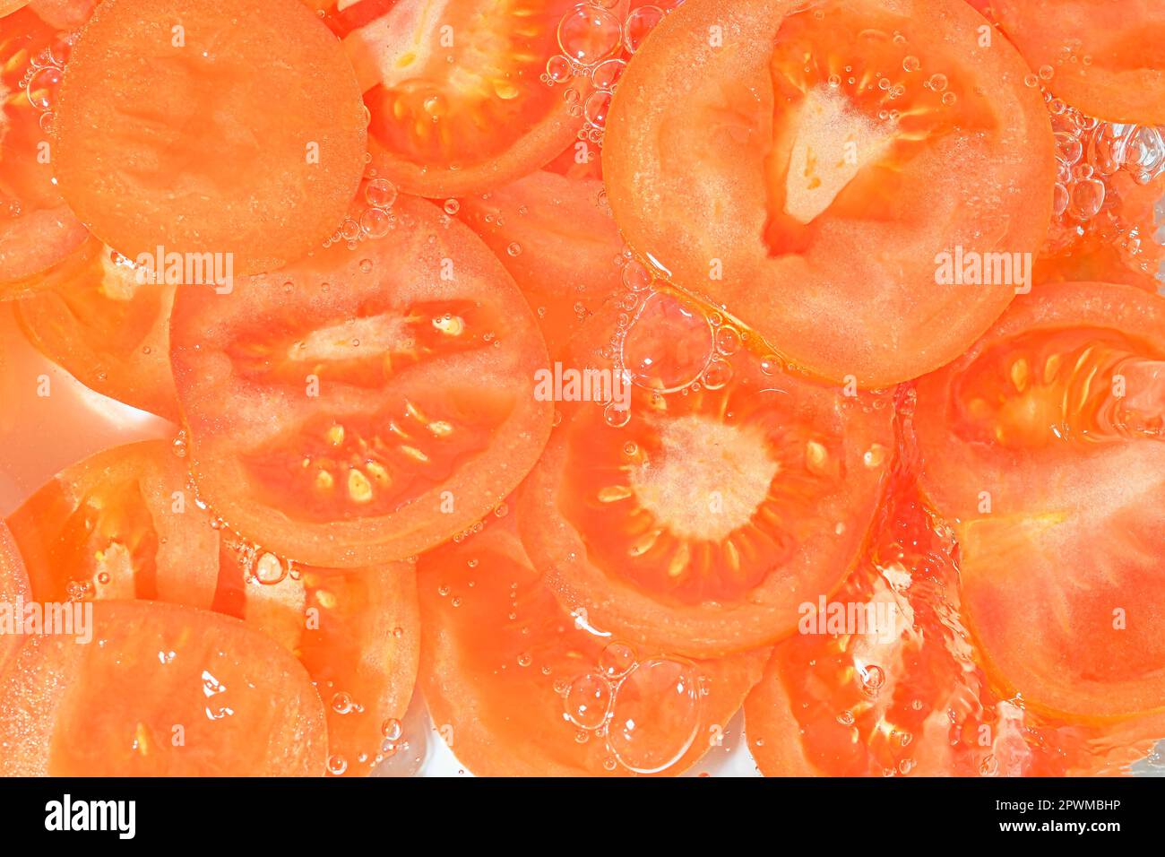 Tranches de tomate dans l'eau sur fond blanc. Gros plan de la tomate ...