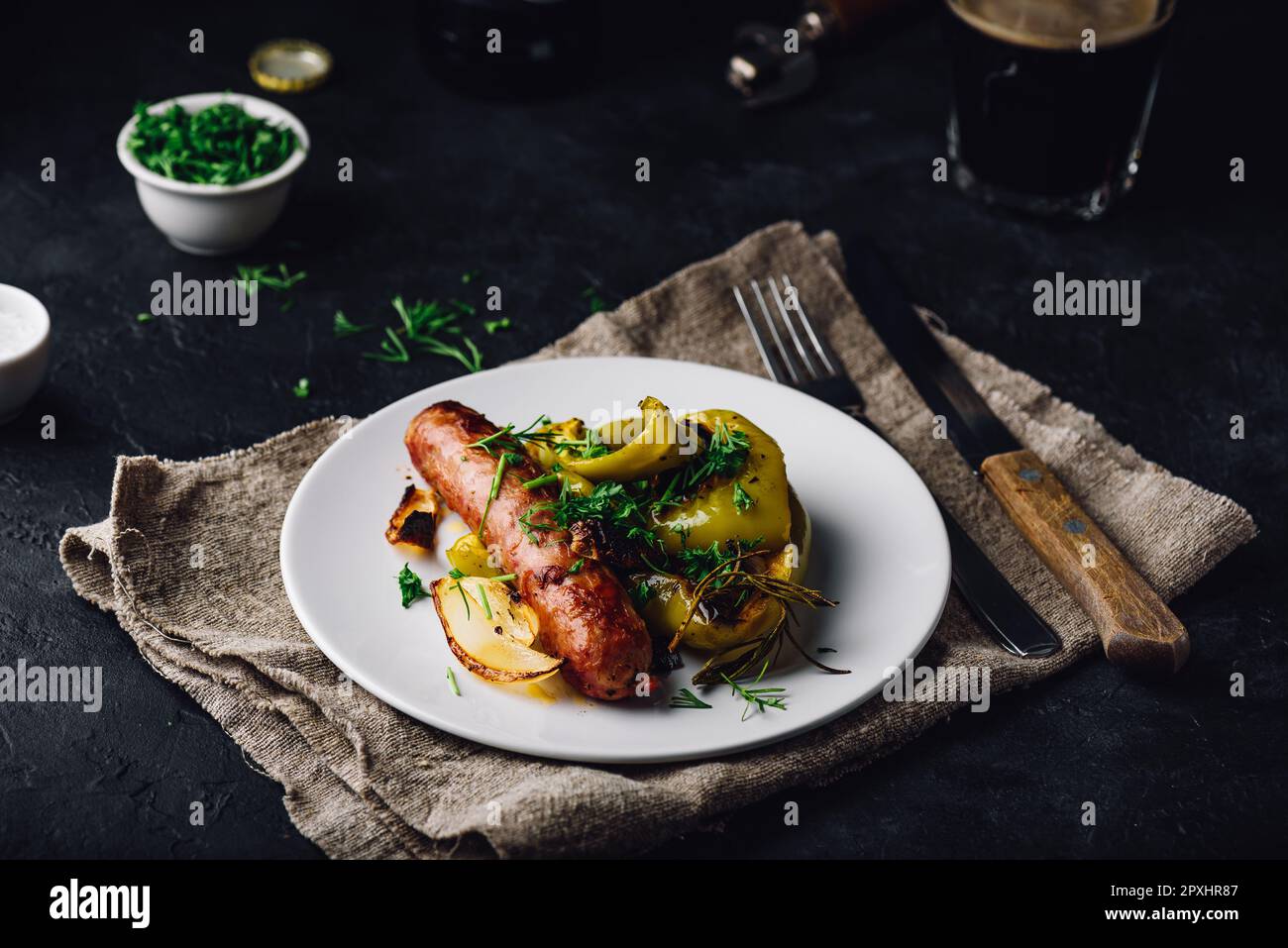 Saucisse de porc cuite au four avec poivrons verts, oignons et herbes sur plaque blanche Photo ...