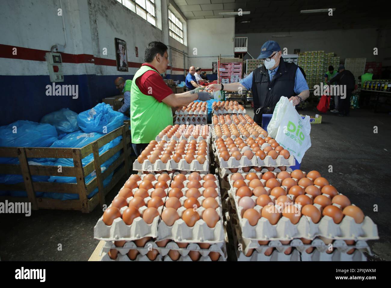 Volunteers attend to people who come looking for food at the warehouse ...