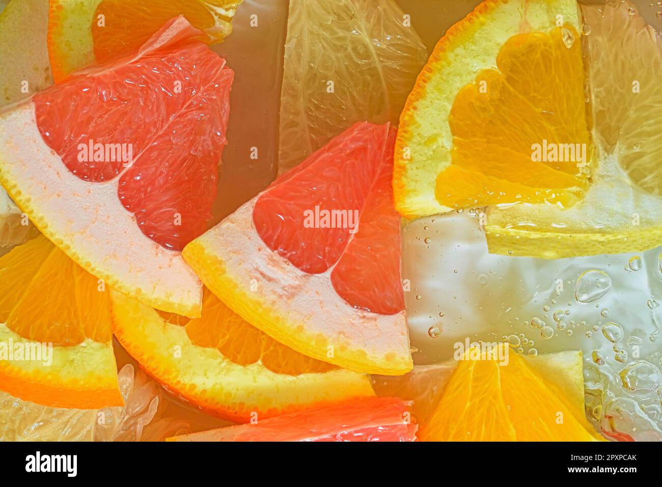Tranches de pamplemousse, d'orange et de pomelo dans l'eau sur fond ...