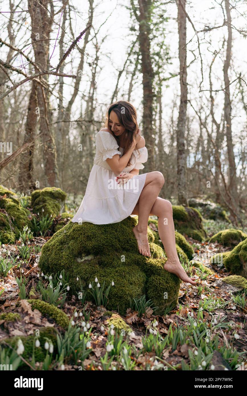 Portrait d'une femme dans la forêt. Elle est assise dans une robe ...