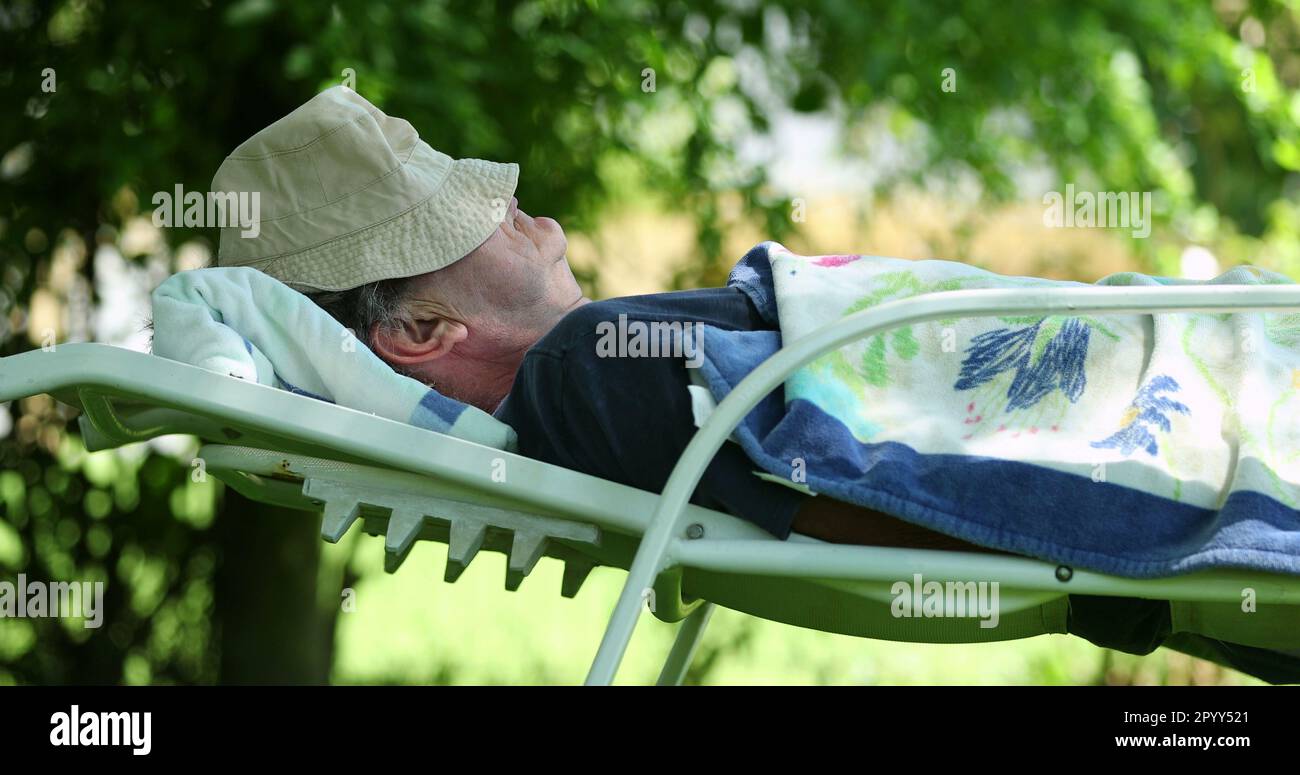 Homme plus âgé qui prend une sieste dehors dans la nature. Personne ...