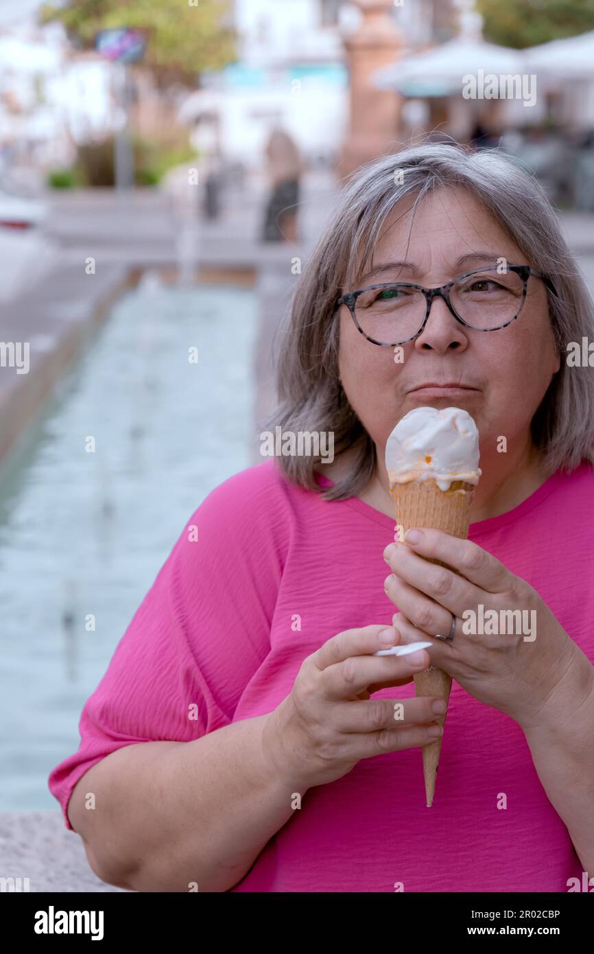 Gros plan d'une femme aux cheveux blancs avec des verres qui mangent de ...