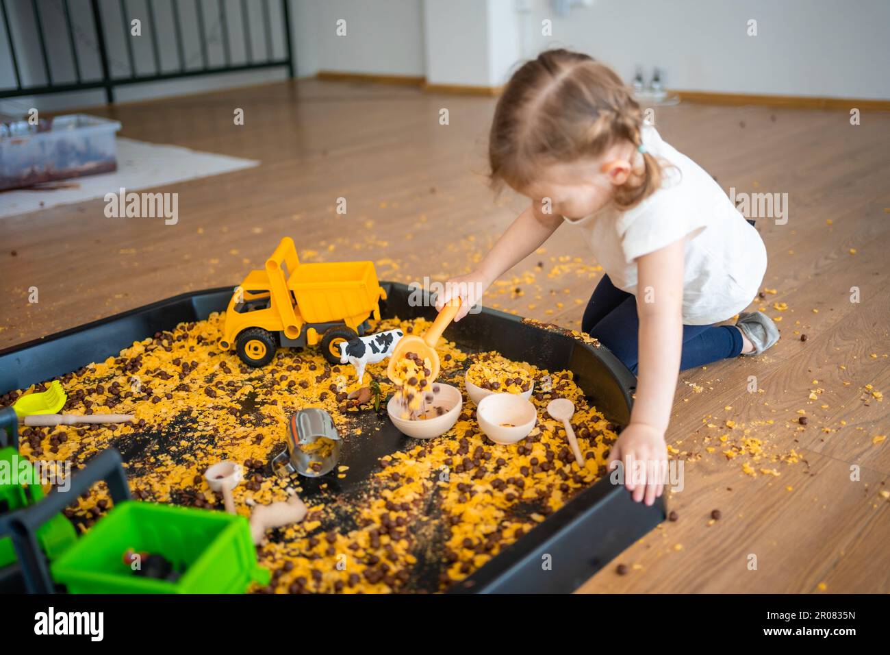 Petite fille jouant avec des flocons sensoriels dans le bac à sable ...