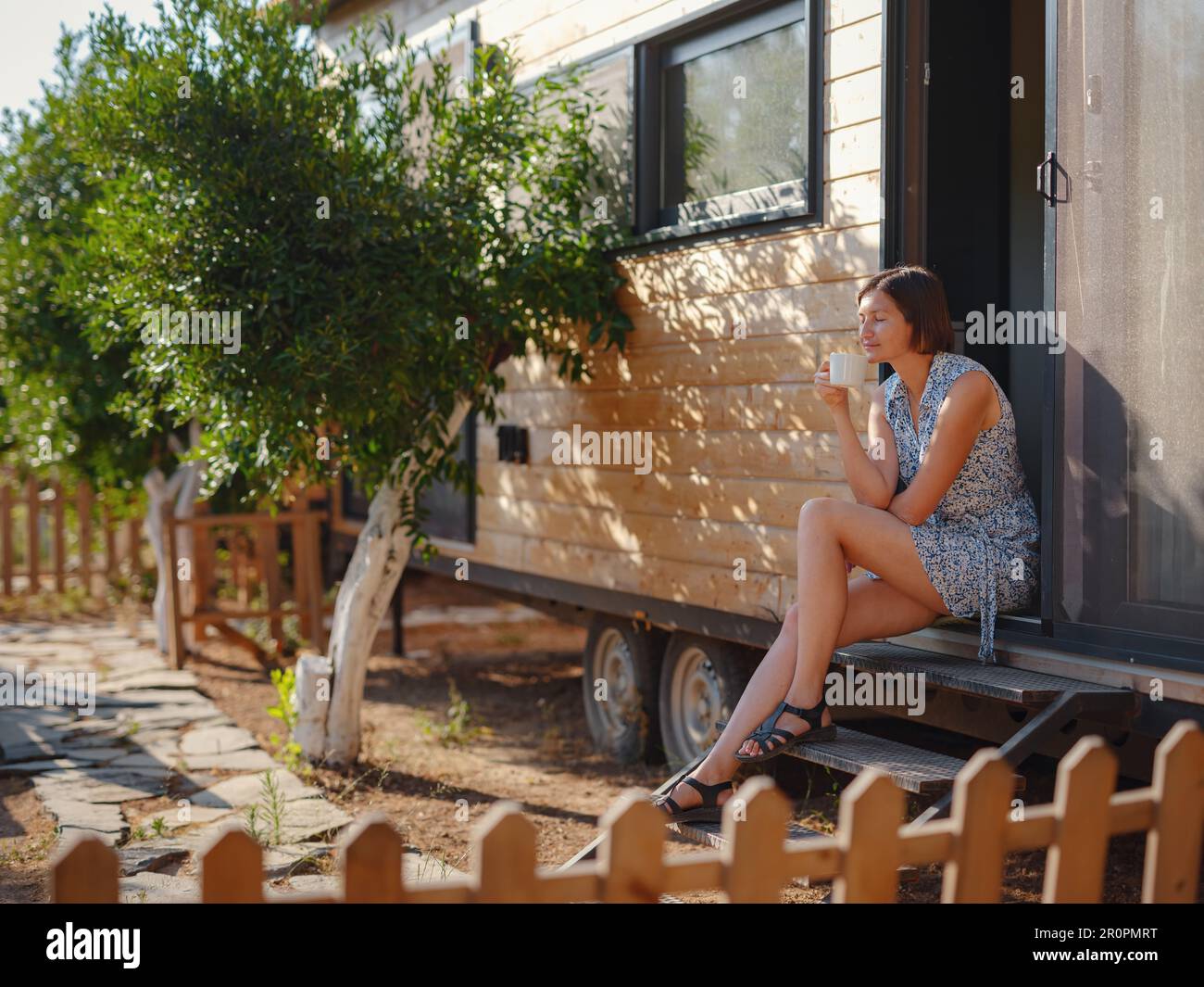 La femme boit du café, la routine du matin près de sa petite maison ... La femme boit du café, la routine du matin près de sa petite maison ...