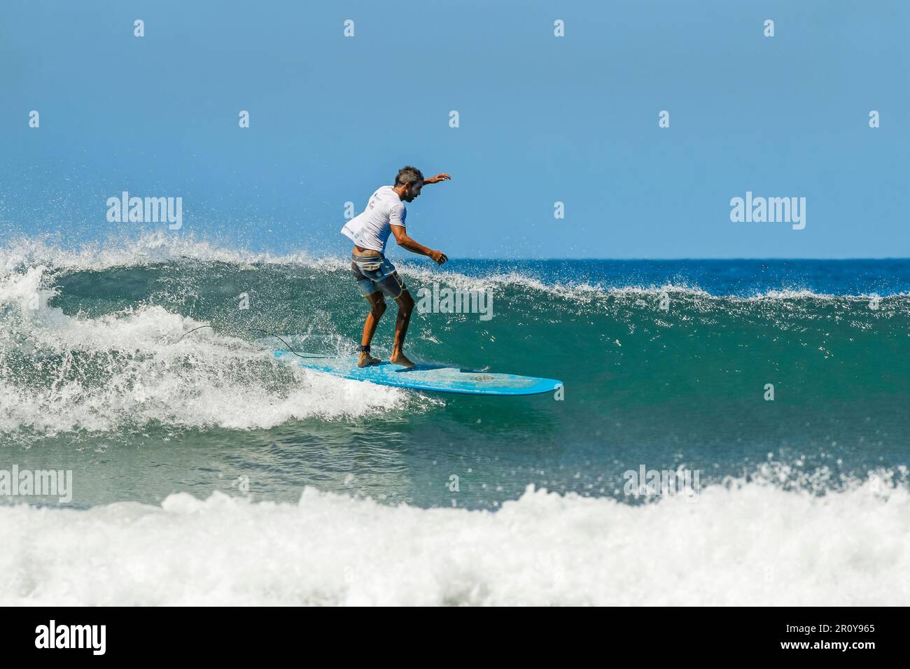Le surfeur de Longboard fait le tour d'une vague sur cette plage de ...