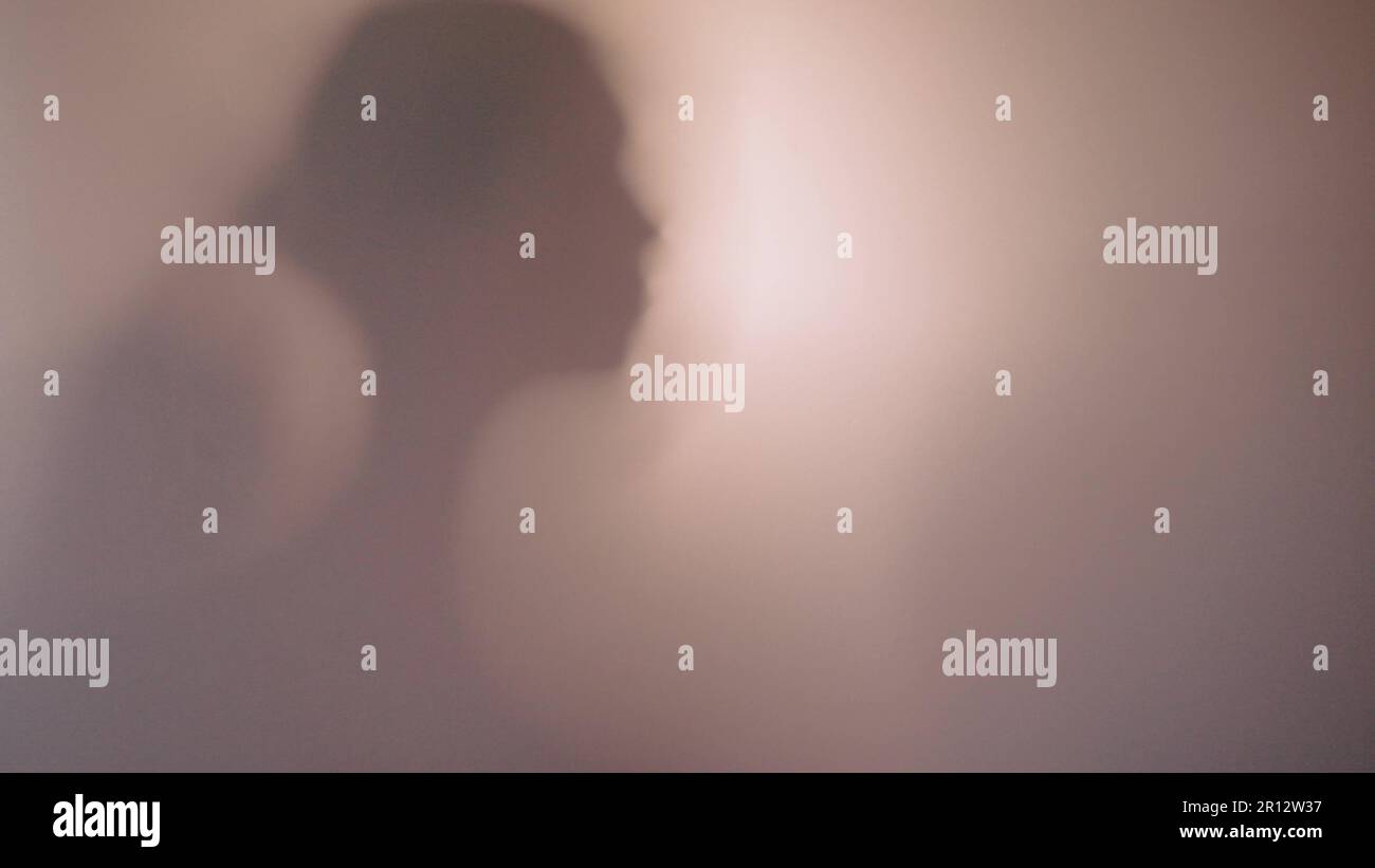 Ombre flou d'un homme d'horreur derrière le verre dépoli. Main floue ...