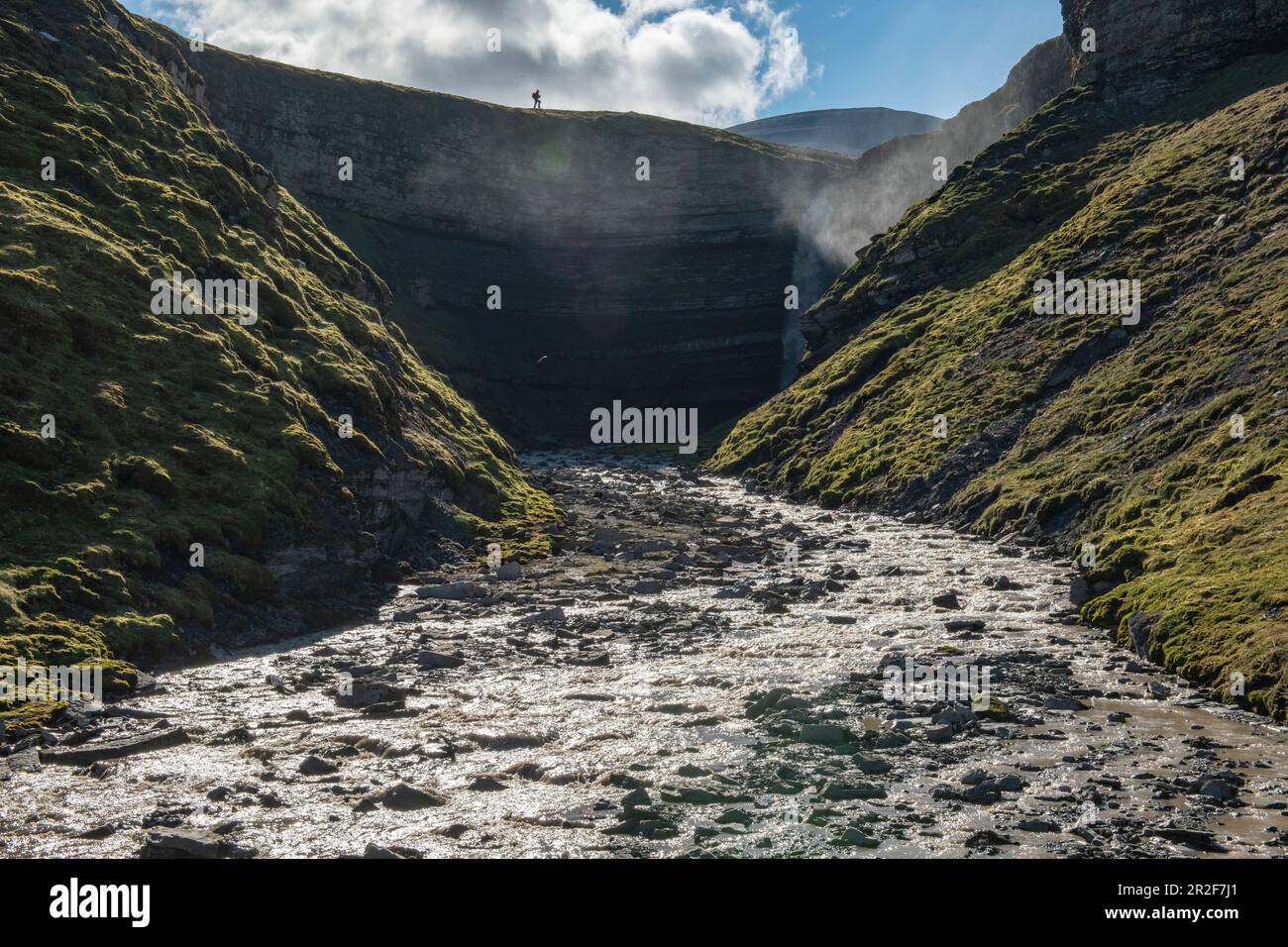 Une rivière coule d'une haute cascade entre des pentes abruptes à l ...