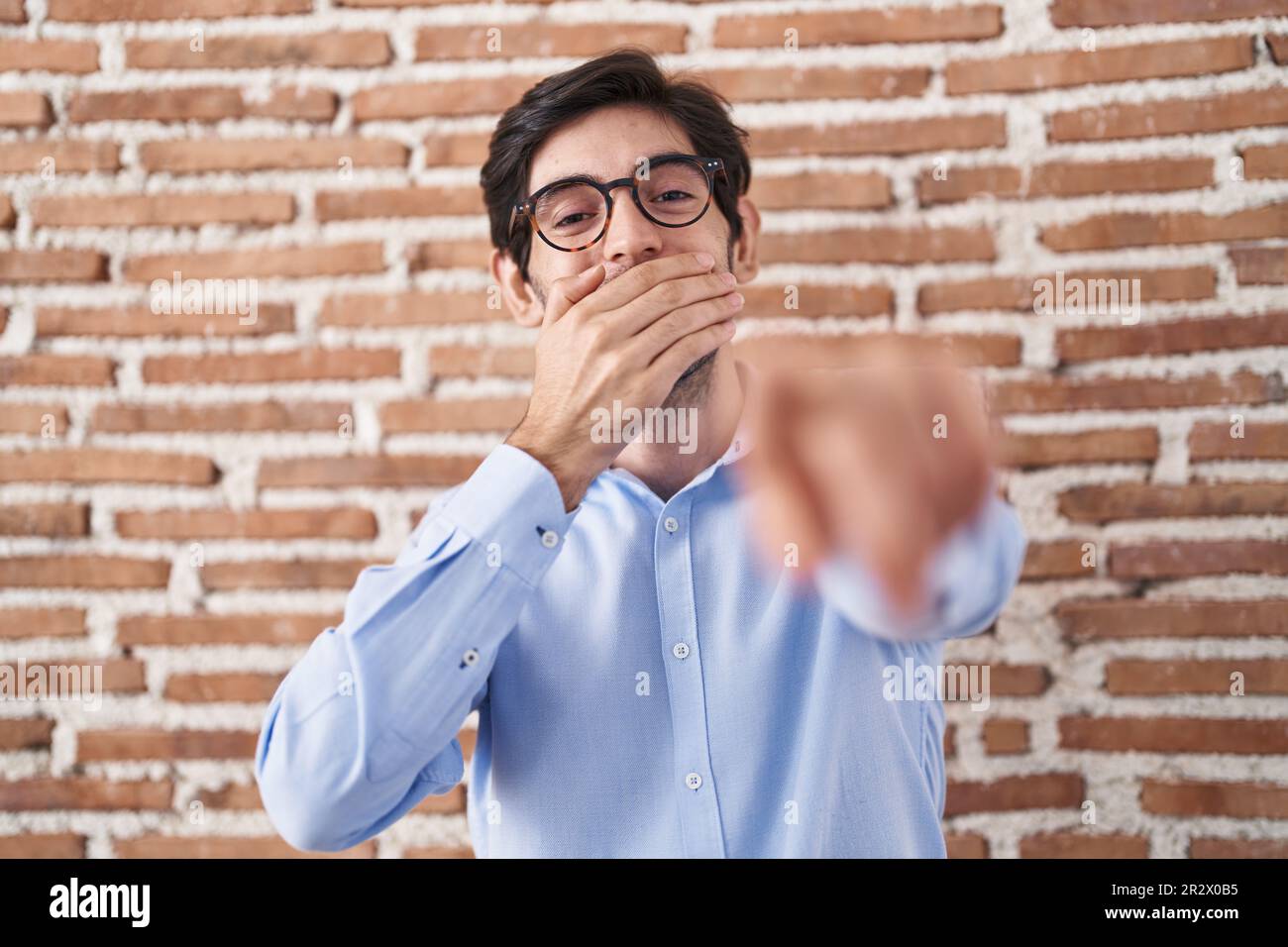 Jeune hispanique homme debout sur le mur de briques arrière-plan riant ...